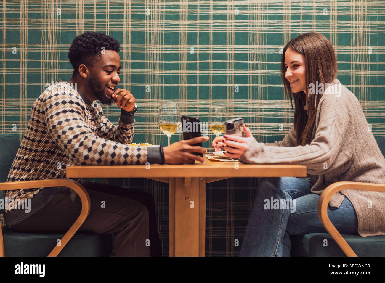 Two friends are having dinner at restaurant. They are sitting, talking ...