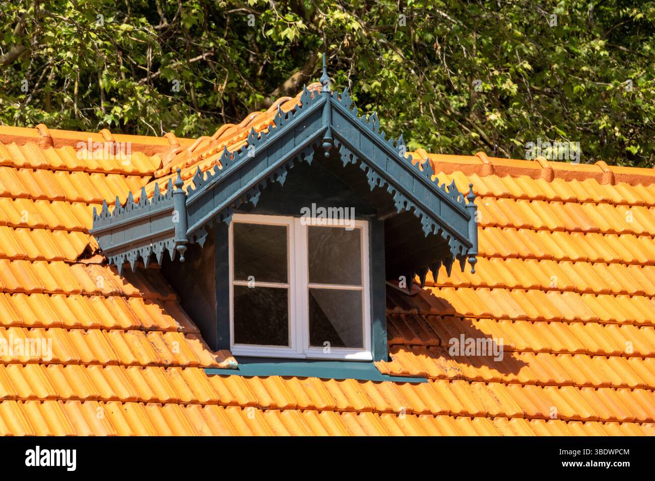 Close up of a dormer window with ornate gable and orange clay roof ...