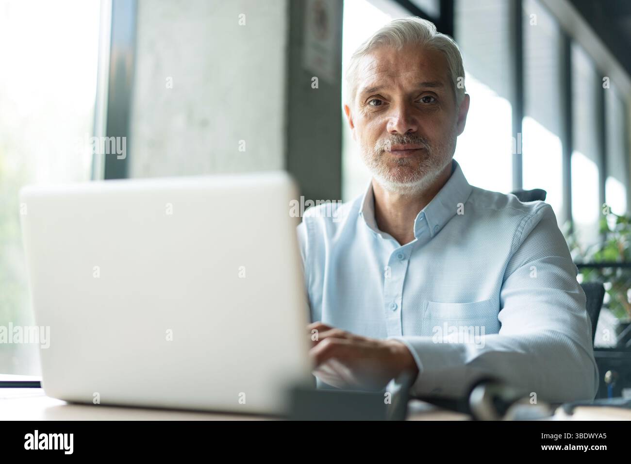 Happy mature professional business man looking at camera sitting at ...