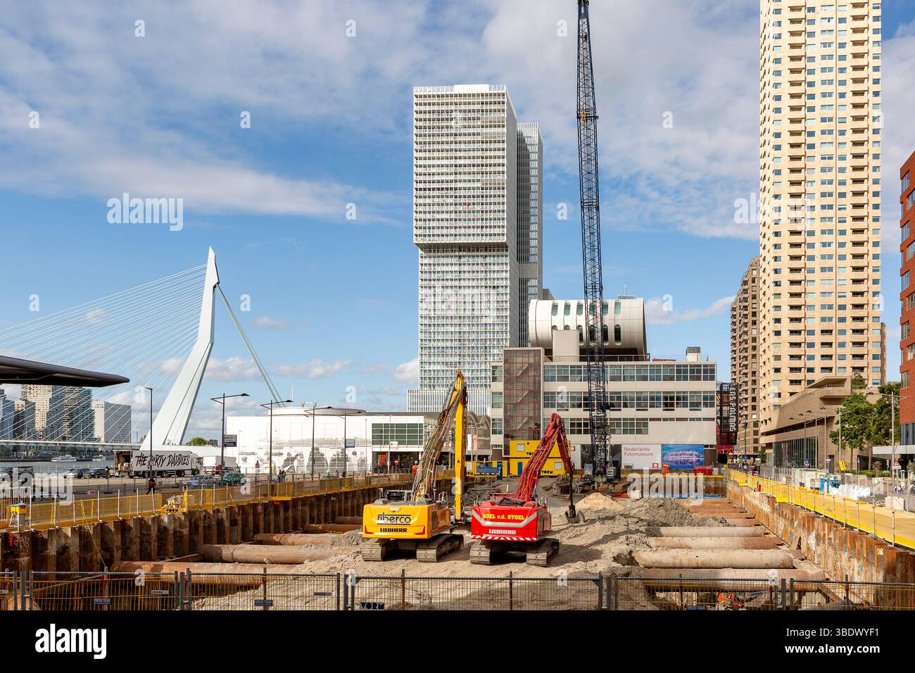 Excavators on plot in front of Erasmus bridge construction site on Kop van Zuid urban island in ...