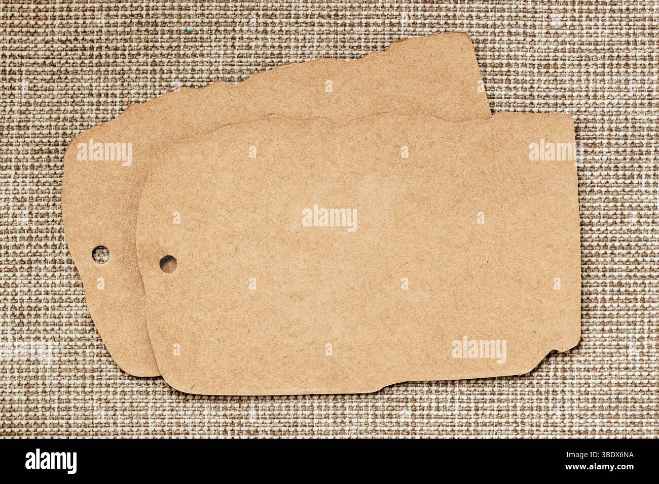 Cardboard labels on burlap. Two blank kraft paper tags with hole on ...