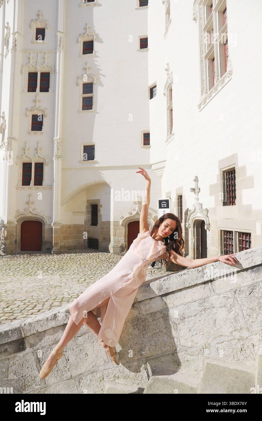 Ballerina balancing gracefully on stone edge near ornate castle wall ...