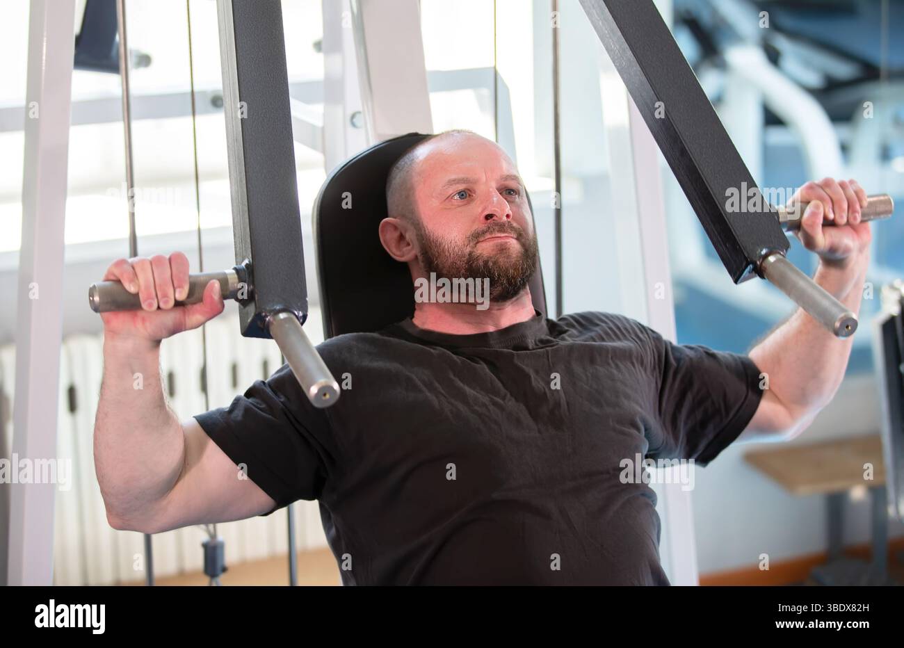 A man is working out at a gym, lifting weights and using a machine. He ...
