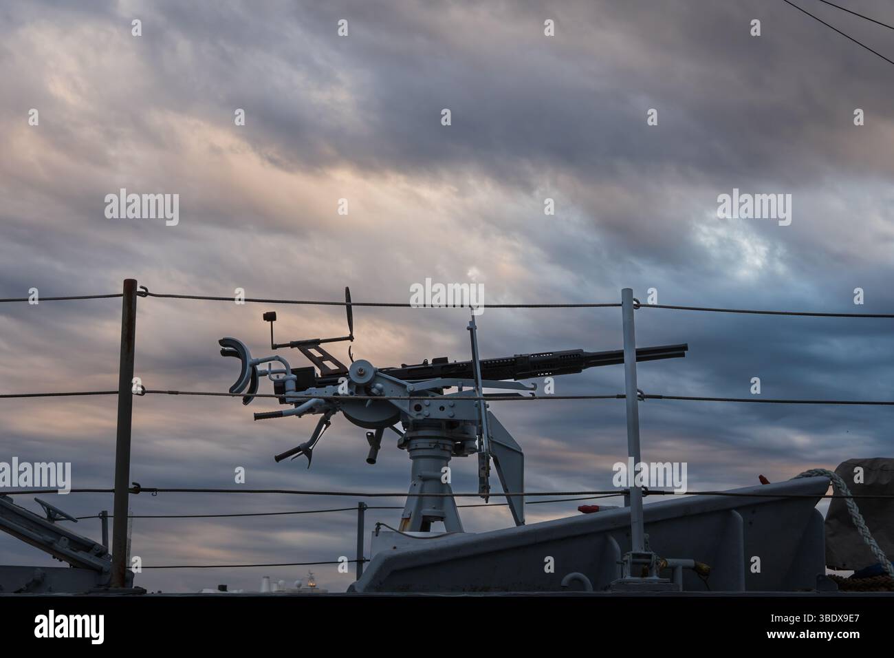 Heavy machine gun on the deck of a warship against a dramatic cloudy ...