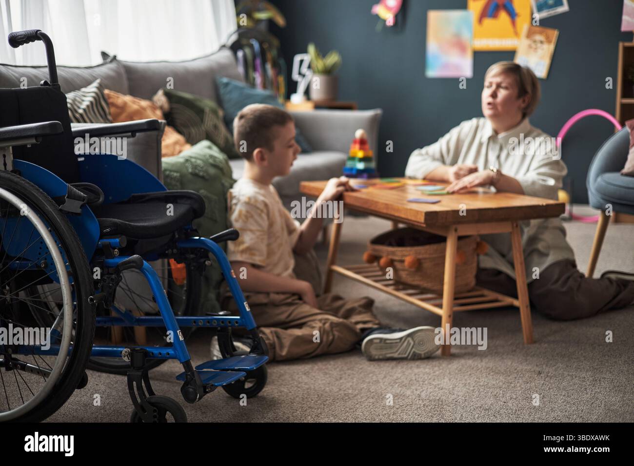 Boy with Disability Playing Cards with Woman at Home Beside Wheelchair ...