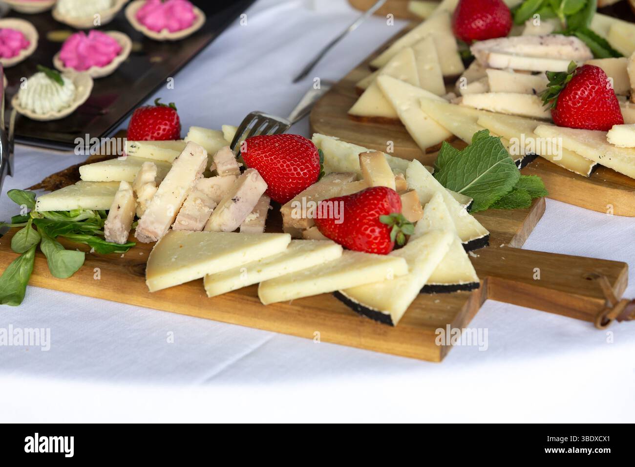 Wooden cheese boards with various cheeses, strawberries, and mint ...