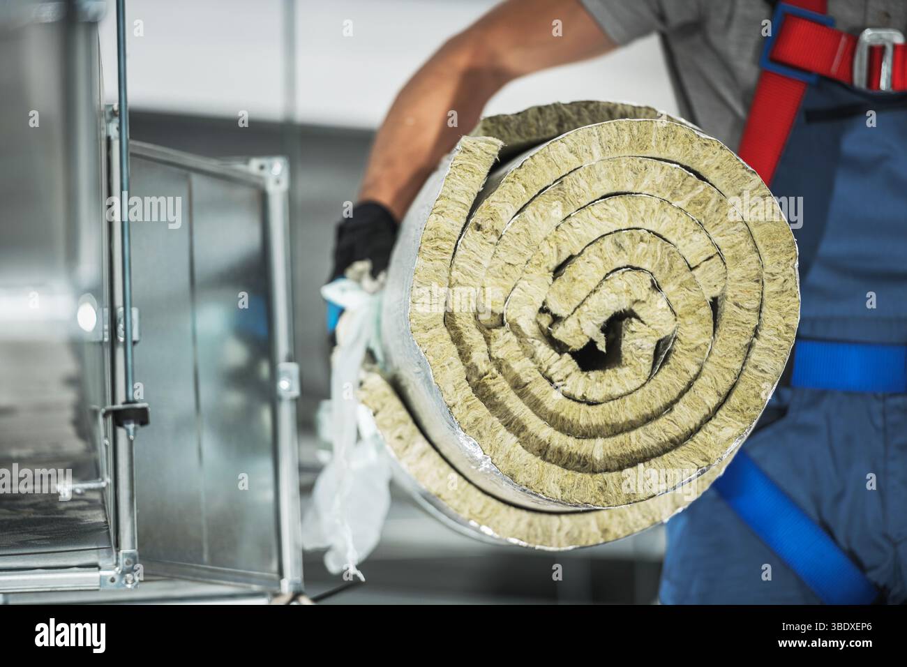 A construction worker carries a rolled insulation material while ...