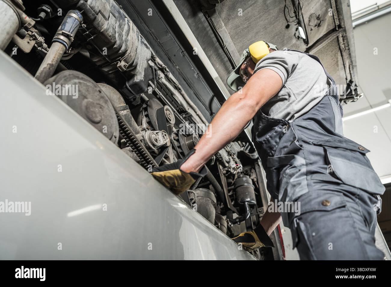 A mechanic inspects and repairs the engine of a vehicle inside a garage ...