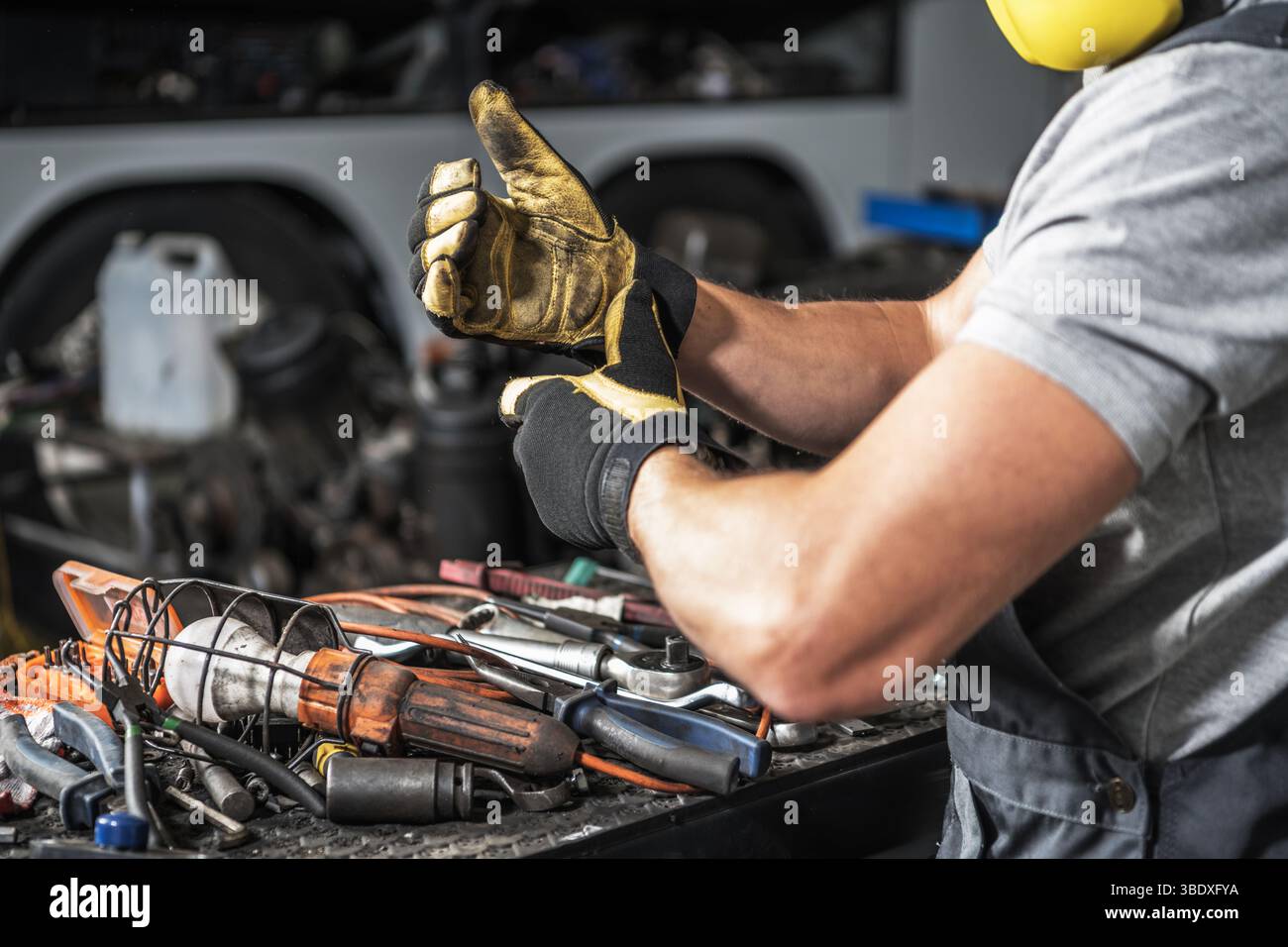 A mechanic is putting on gloves while getting ready to work on vehicles ...
