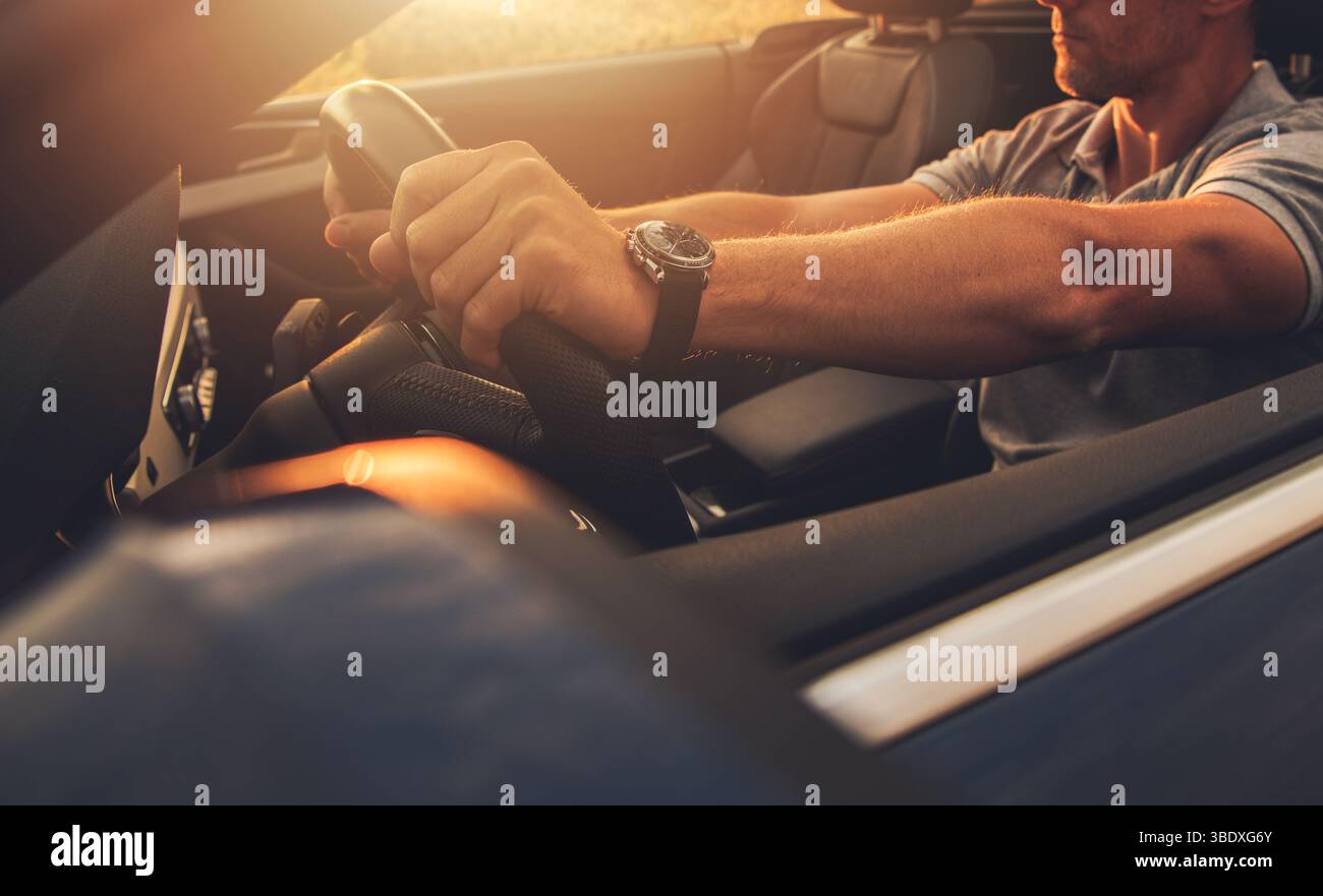 A person grips the steering wheel of a car, enjoying a leisurely drive ...