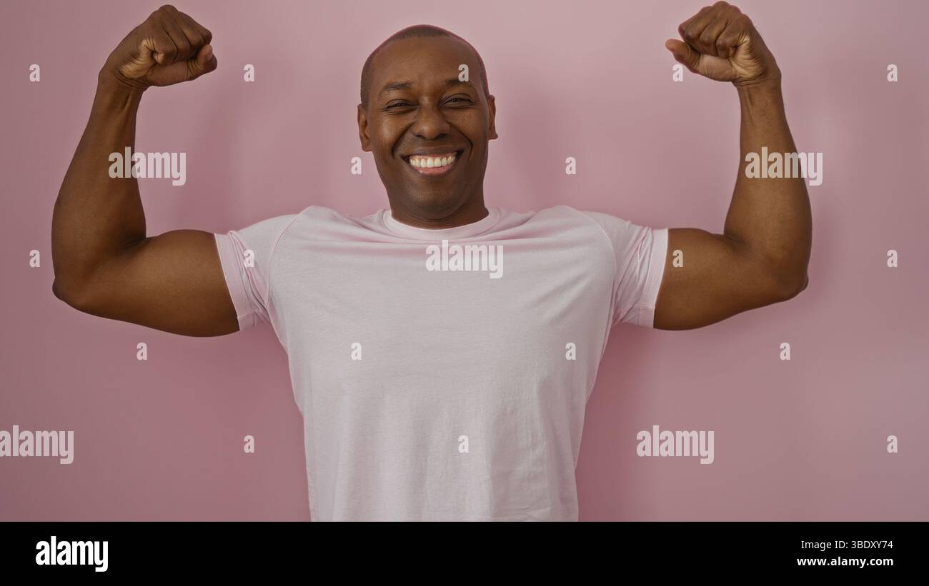 Smiling man flexes muscles confidently against a vibrant pink wall ...