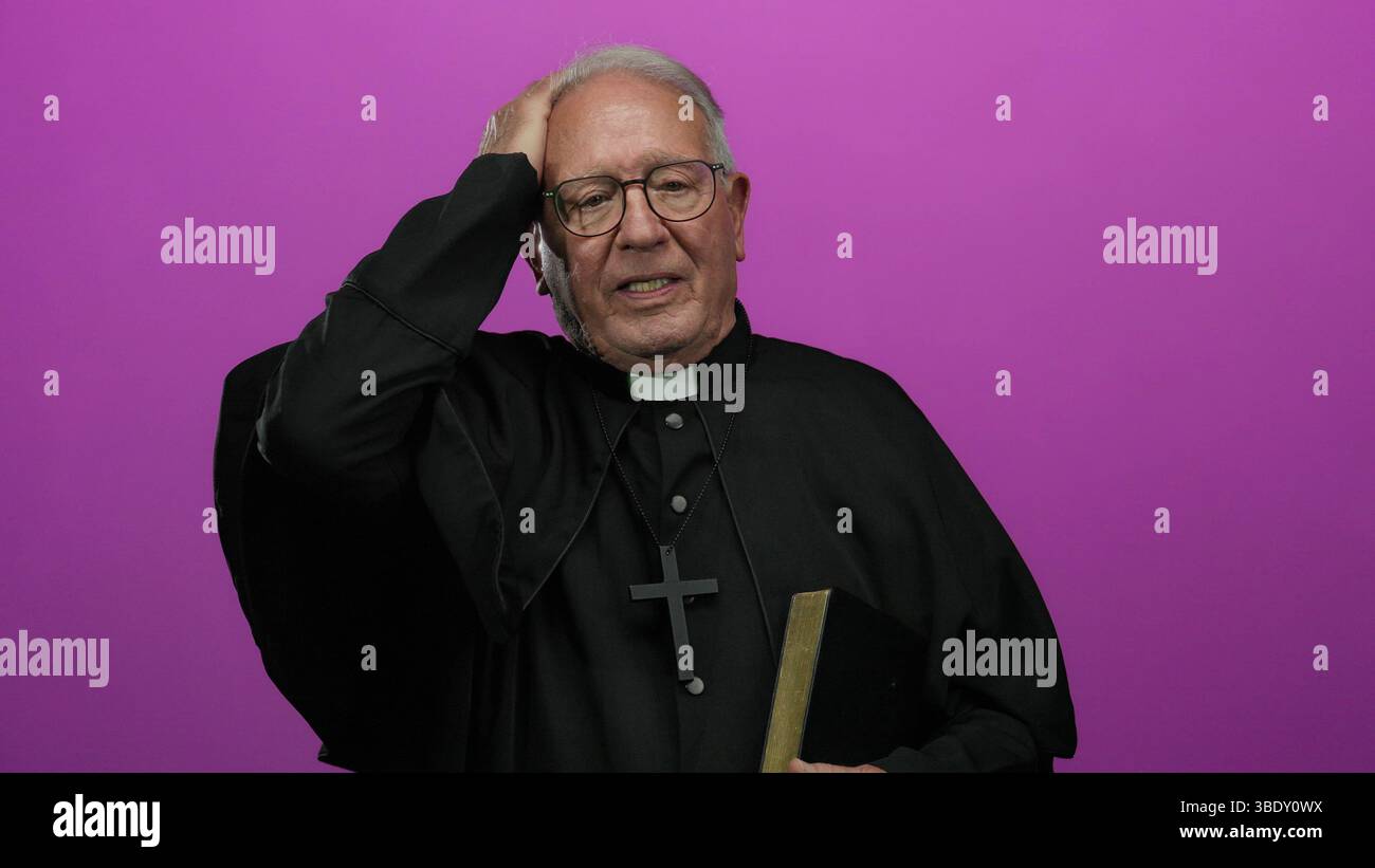 Senior priest in black robe, holding a book, stands over an isolated ...