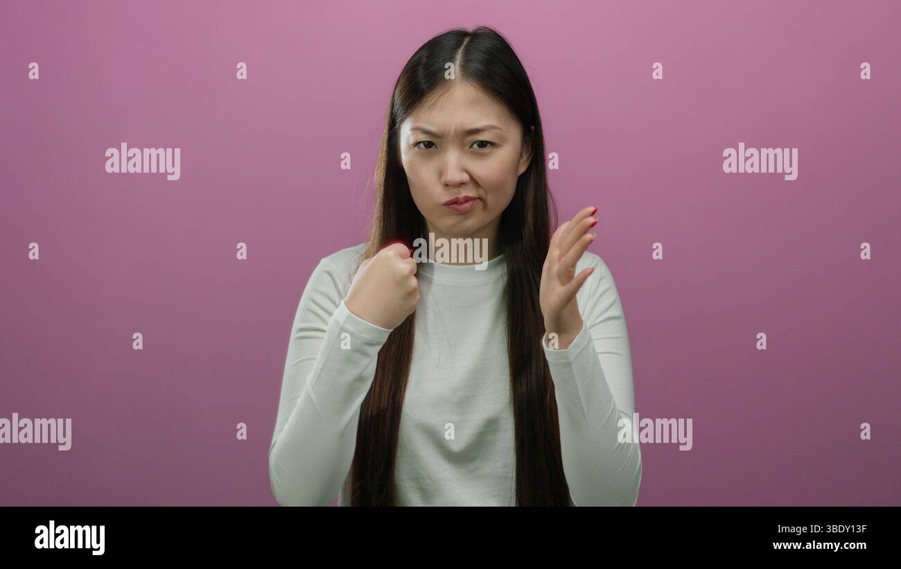 Woman expressing determination with closed fists against a vibrant pink ...