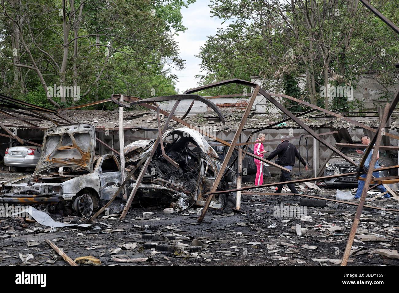 People stay by cars destroyed by an overnight Russian drone strike in ...