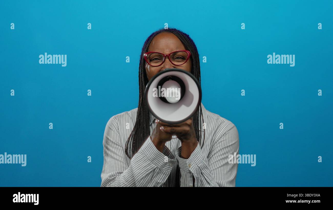 Woman shouting through megaphone against blue background wearing ...