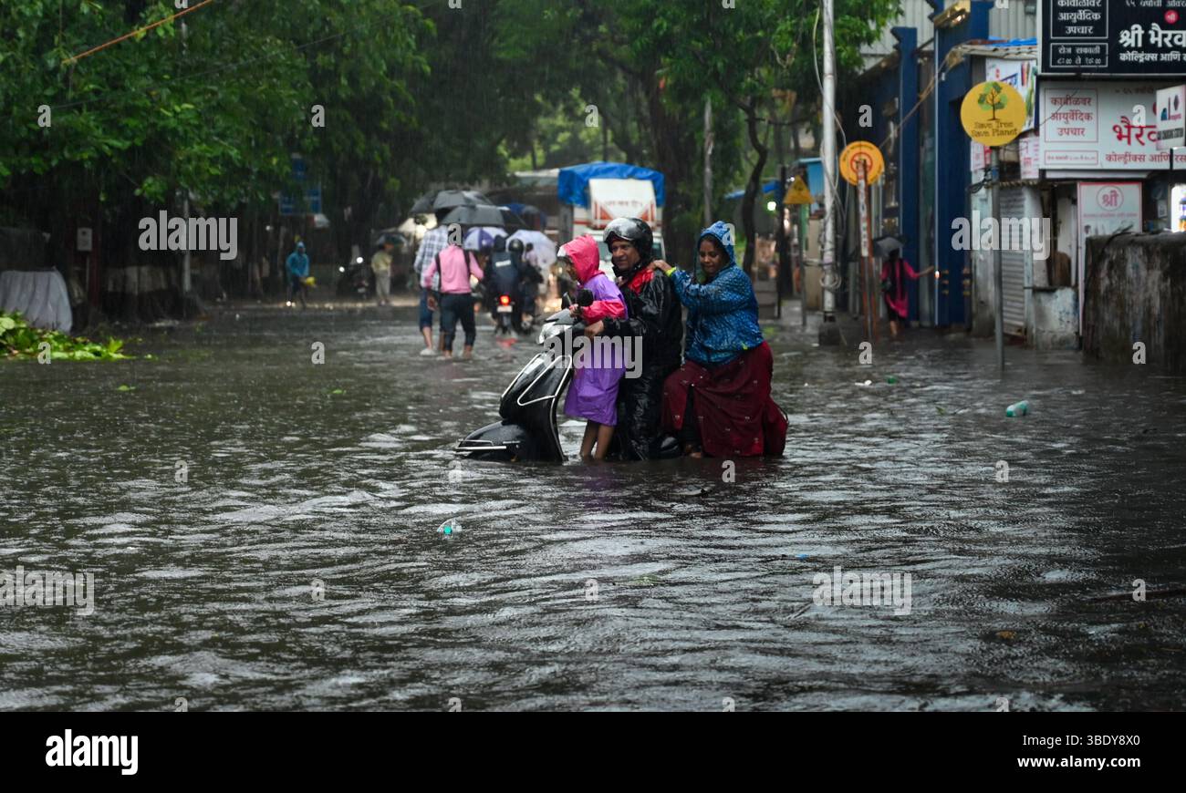 MUMBAI, INDIA - MAY 26: A family wade through waterlogged road at Gandhi Market in the Sion area ...