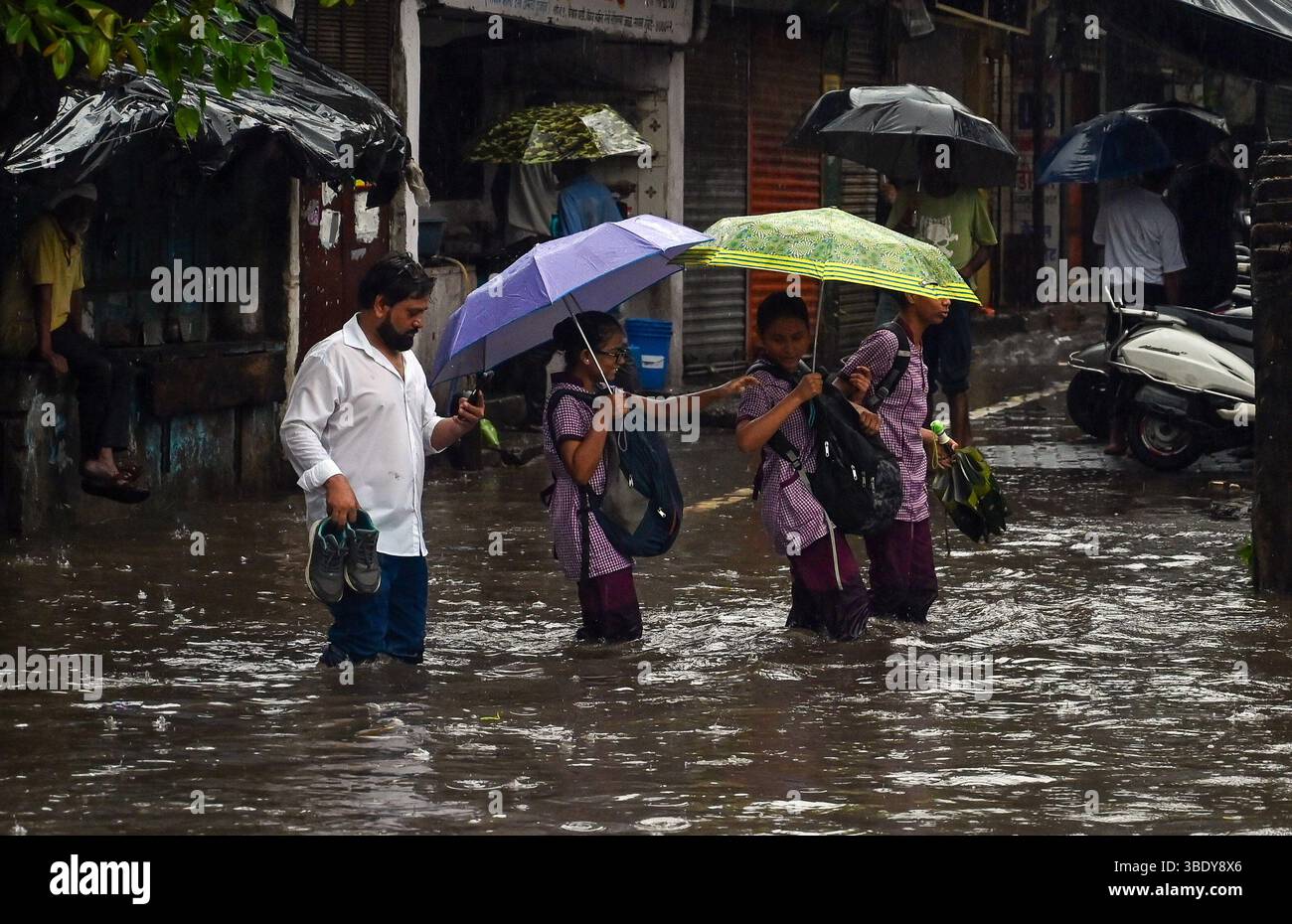 MUMBAI, INDIA - MAY 26: People wade through waterlogged road at Gandhi Market in the Sion area ...