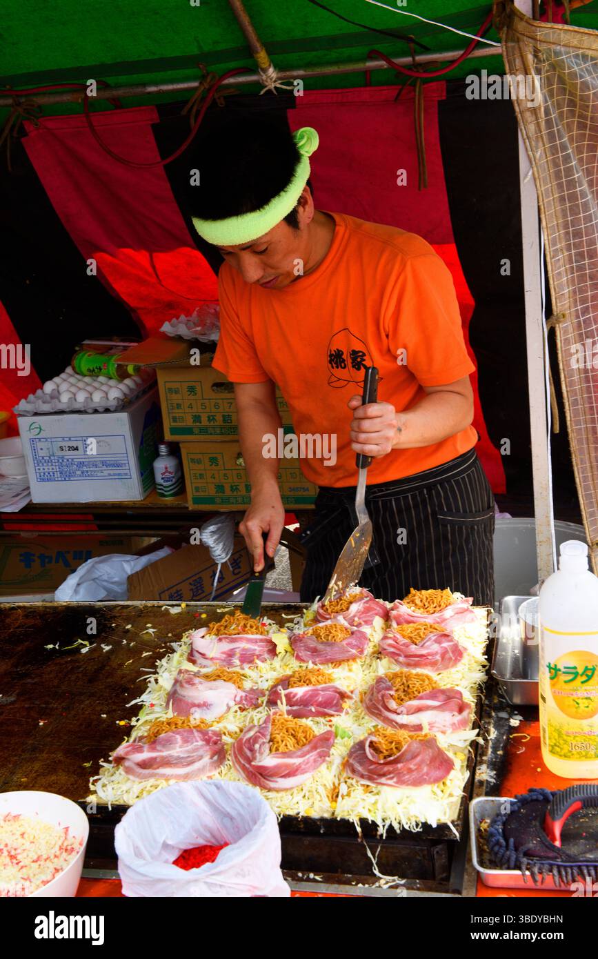 Japanese street food vendor cooking okonomiyaki cabbage pancakes at ...