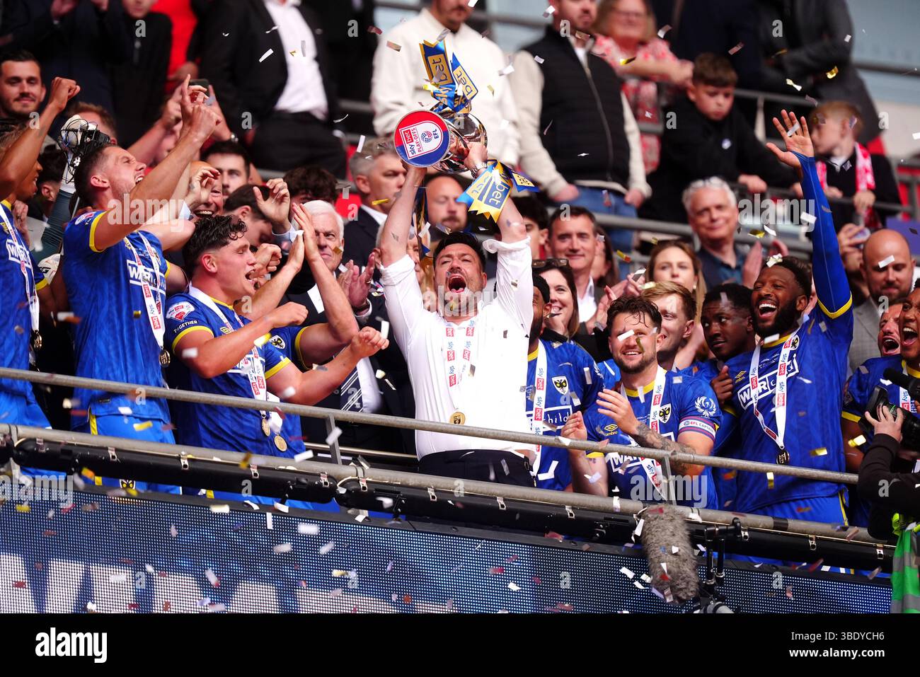 AFC Wimbledon manager Johnnie Jackson (centre) lifts the trophy with ...