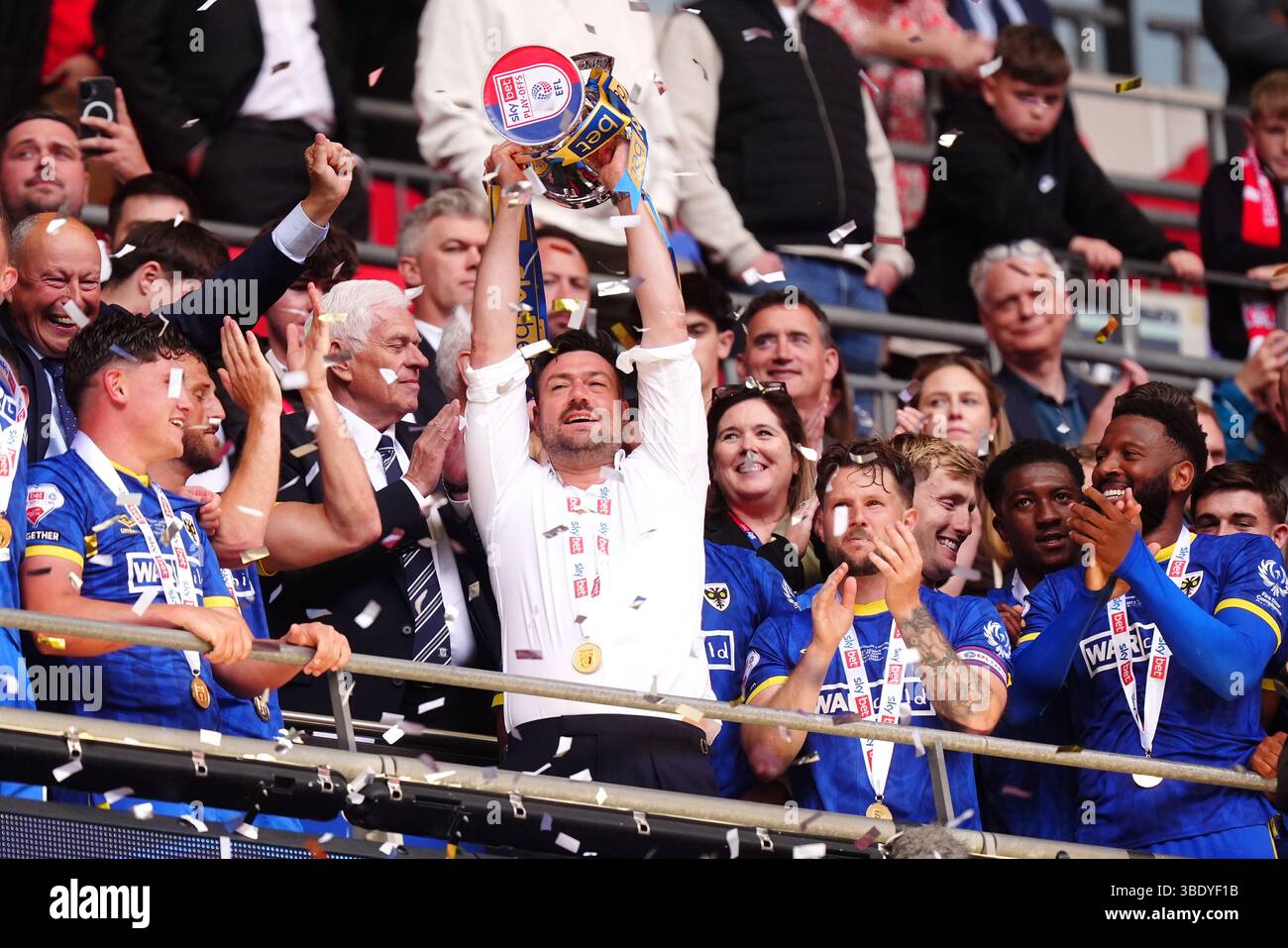 AFC Wimbledon manager Johnnie Jackson (centre) lifts the trophy with ...