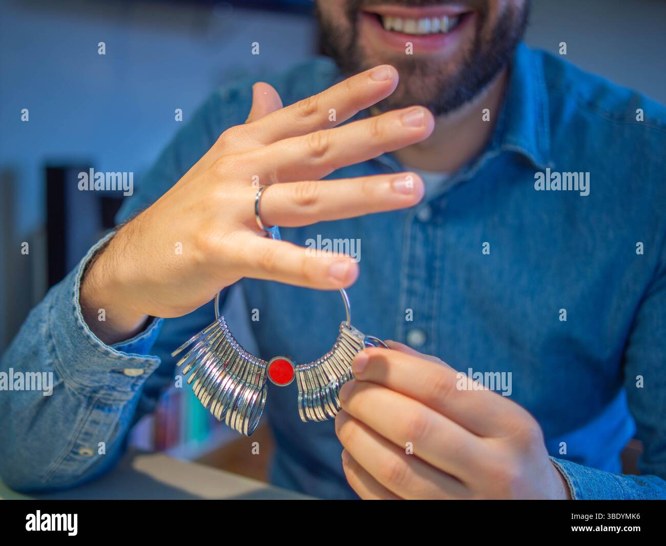 Man measuring his finger with a ring sizer Stock Photo - Alamy