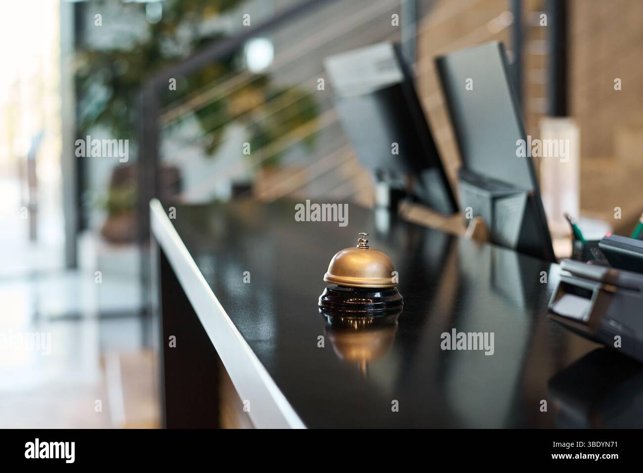 Gold bell on modern hotel reception desk reflecting ambient light ...