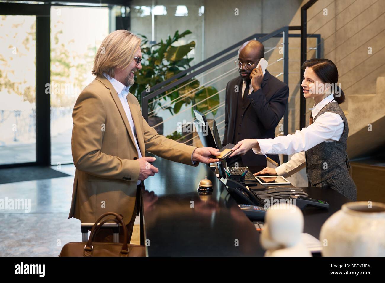 Businessman making payment at hotel reception desk while receiving ...