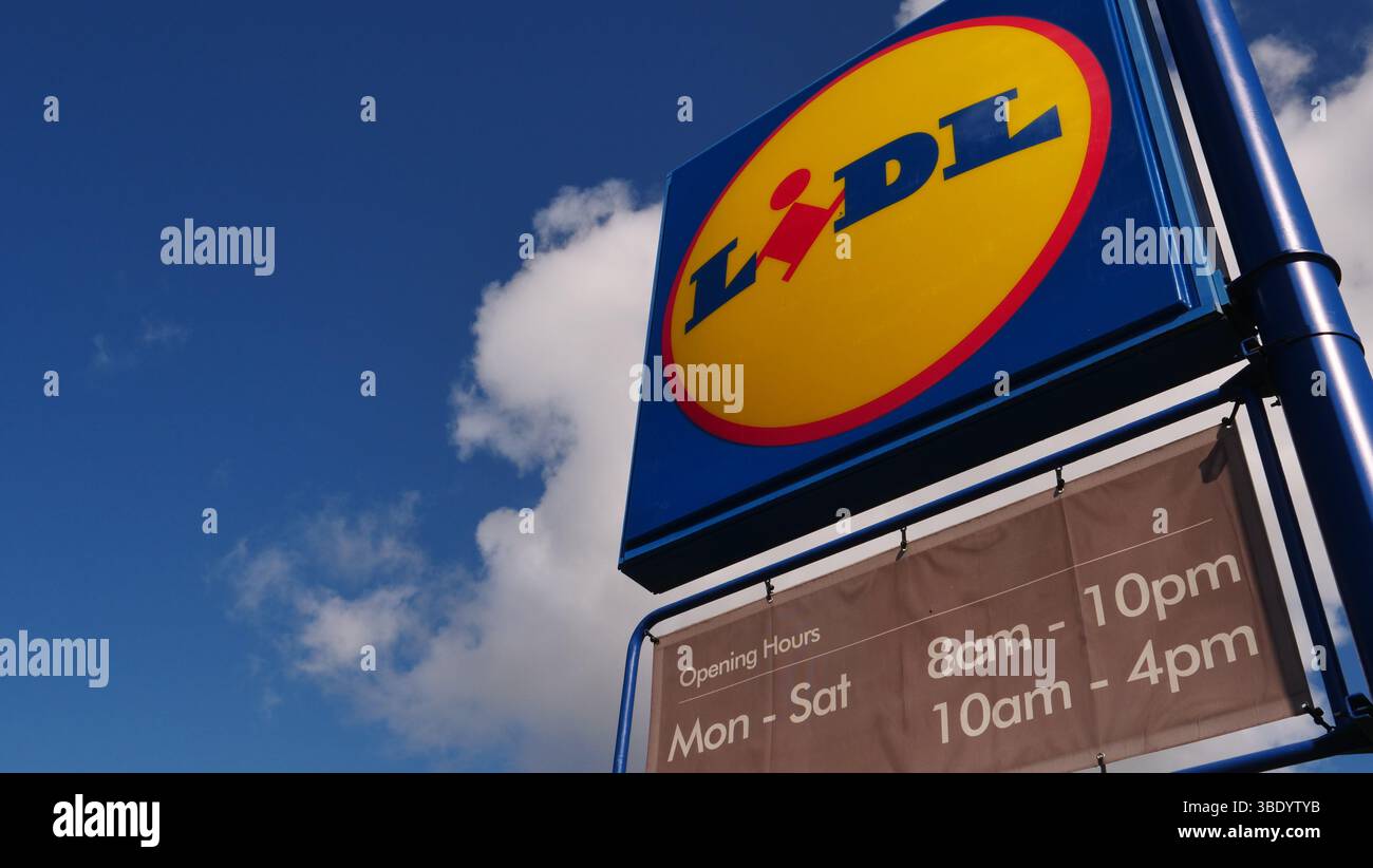 The logo and signage of the Lidl grocery store against a blue sky ...