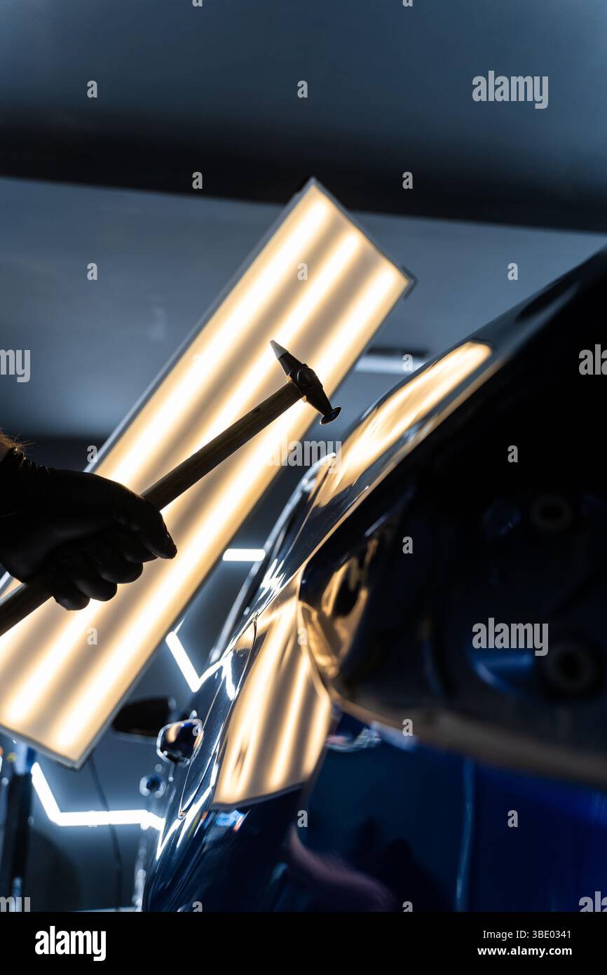 Paintless dent repair PDR involves tapping dents under light reflection for precision ...