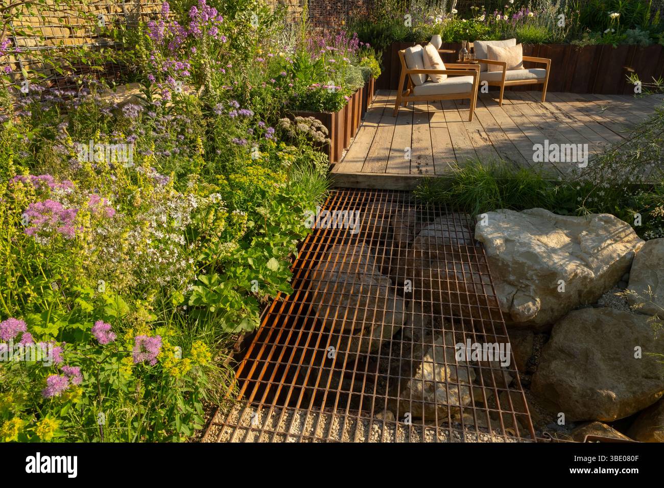 A seating area on a wooden deck surrounded by wildflower borders, a ...