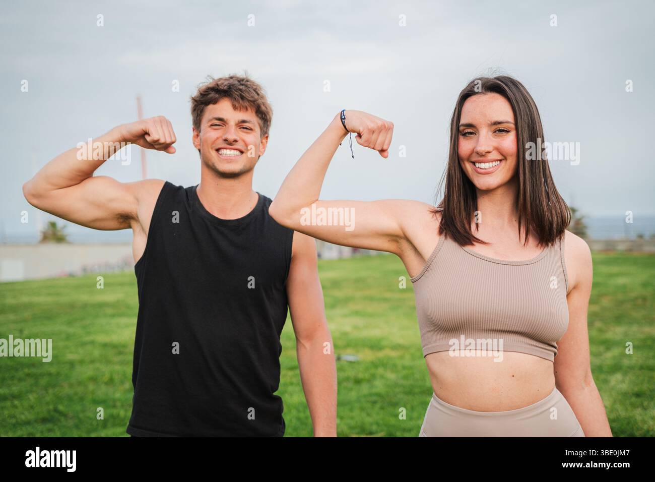 A fit couple demonstrates their strength and fitness by flexing their ...