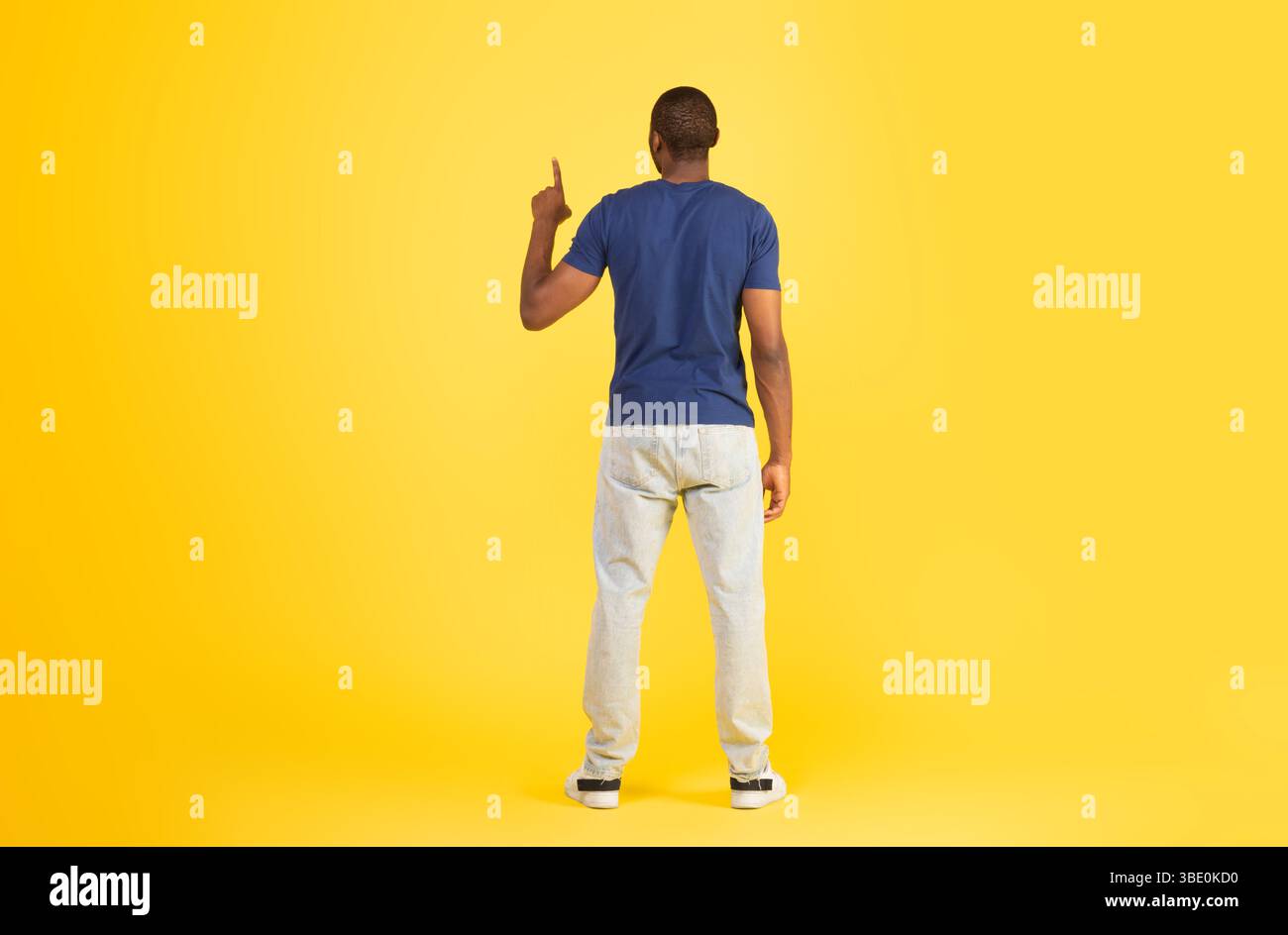 African Man Pointing Finger Up Over Yellow Background, Back View Stock ...