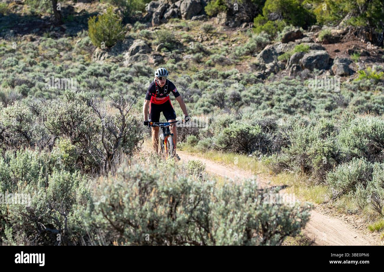 May 25, 2025. Mountain bike cyclist crosses through high desert terrain ...