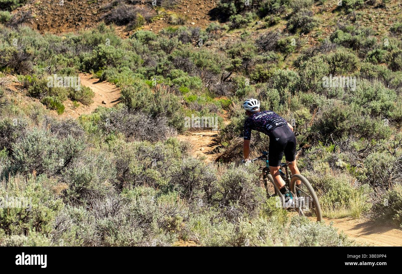 May 25, 2025. Mountain bike cyclist crosses through high desert terrain ...