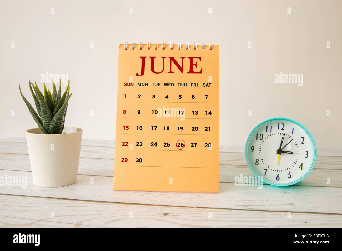 Hand holding a wooden block calendar with the date June 26 on green ...