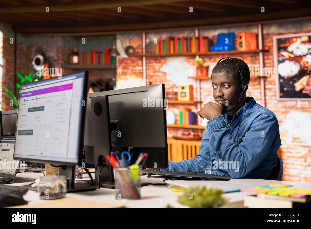 Call center staff member tracking shipments in office, looking at PC ...