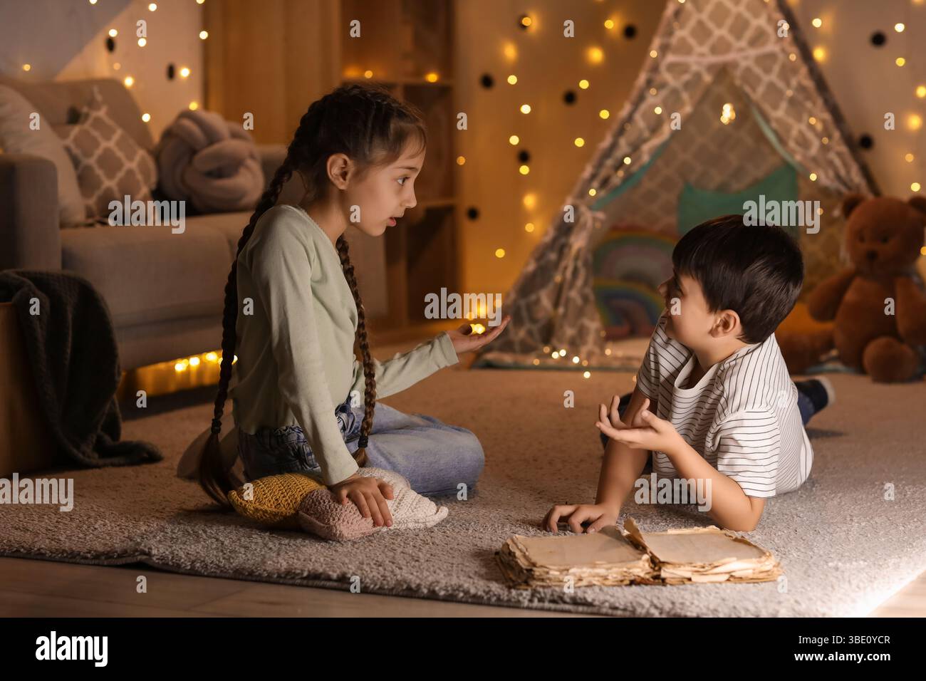 Cute children reading adventure book at home in evening Stock Photo - Alamy