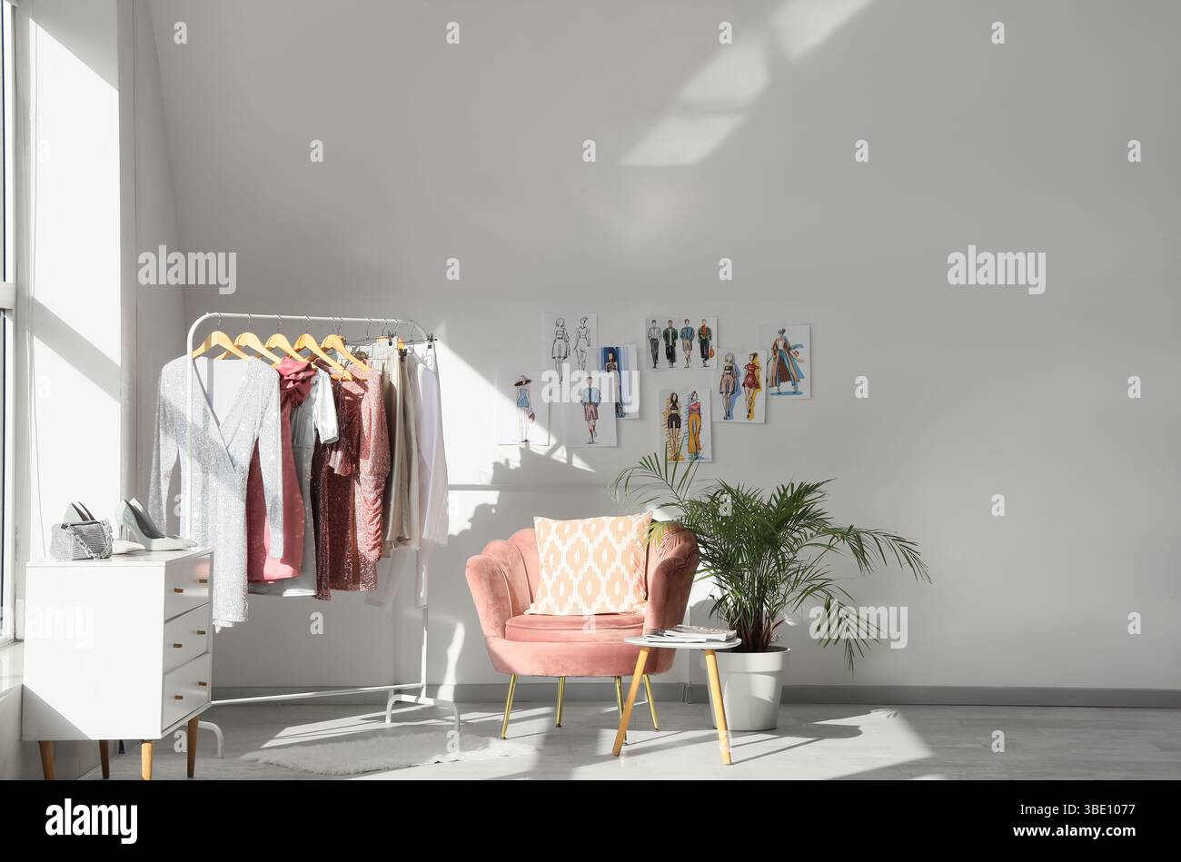 Interior of stylist's studio with clothes rack, armchair and drawings ...