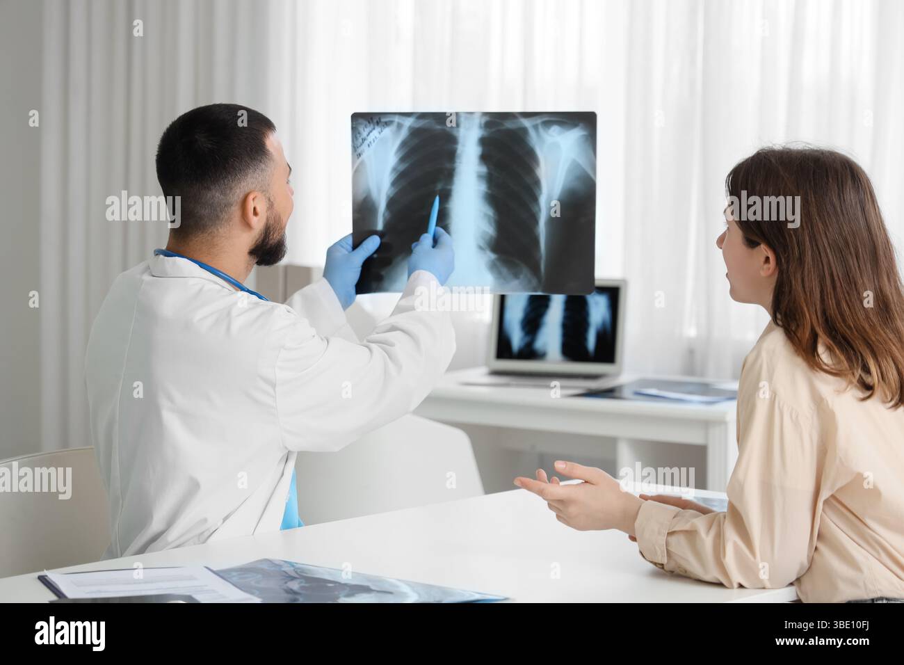 Male doctor showing x-ray scan of lungs to female patient in clinic ...