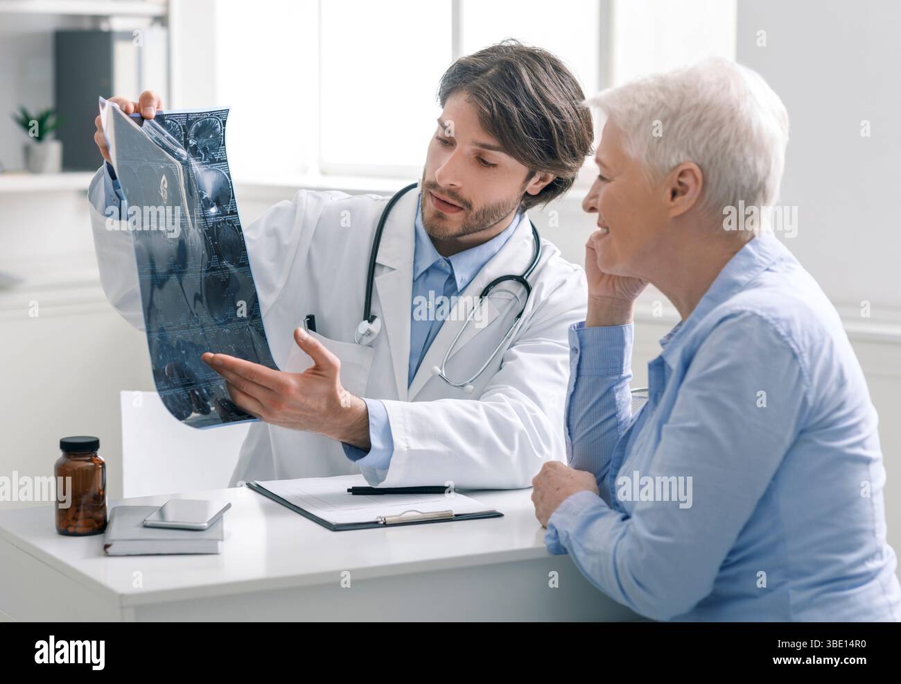 Doctor showing x-ray scans of head to senior female patient Stock Photo ...