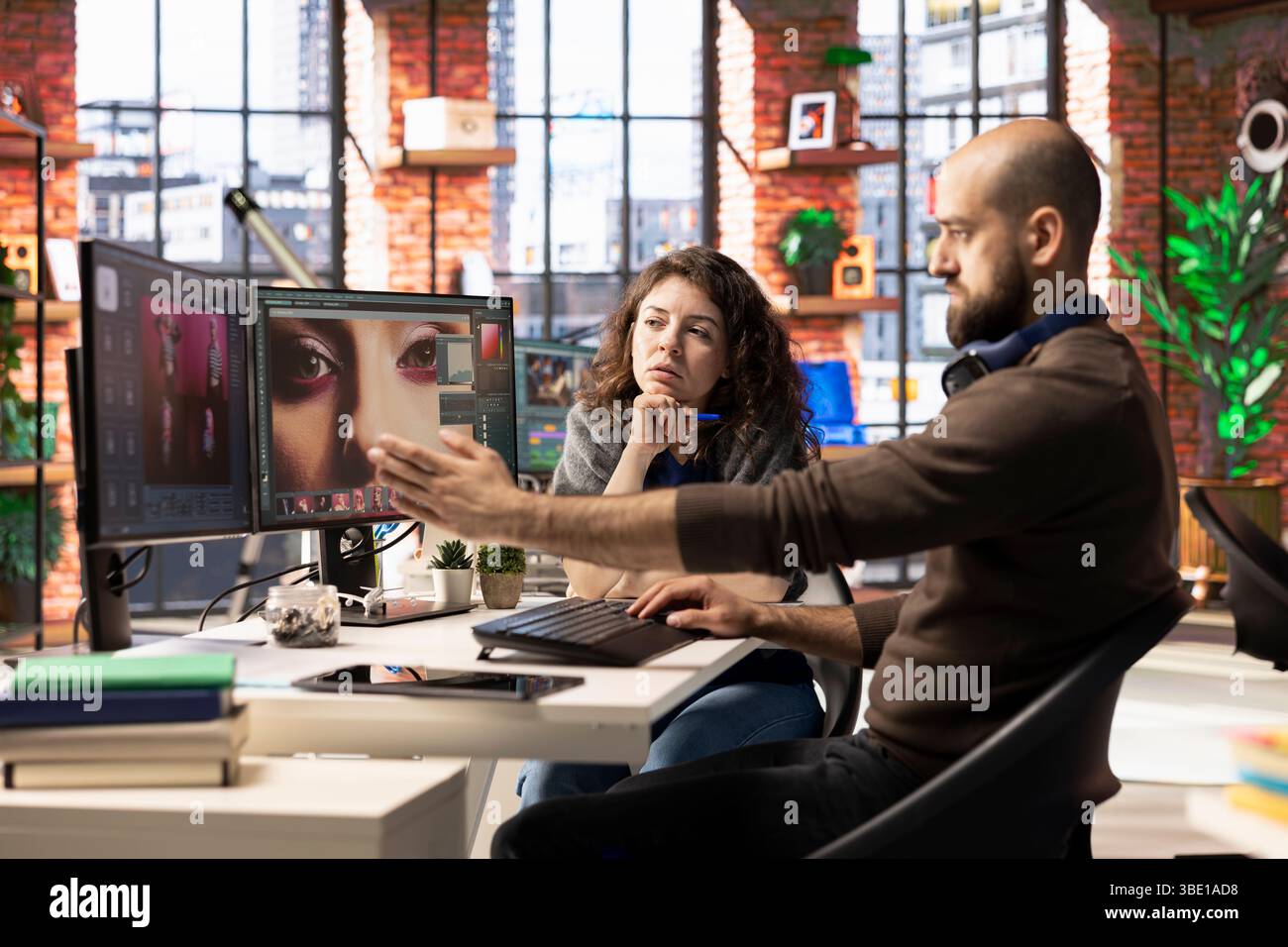 Graphic designer and photographer collaborate in a modern studio, using ...