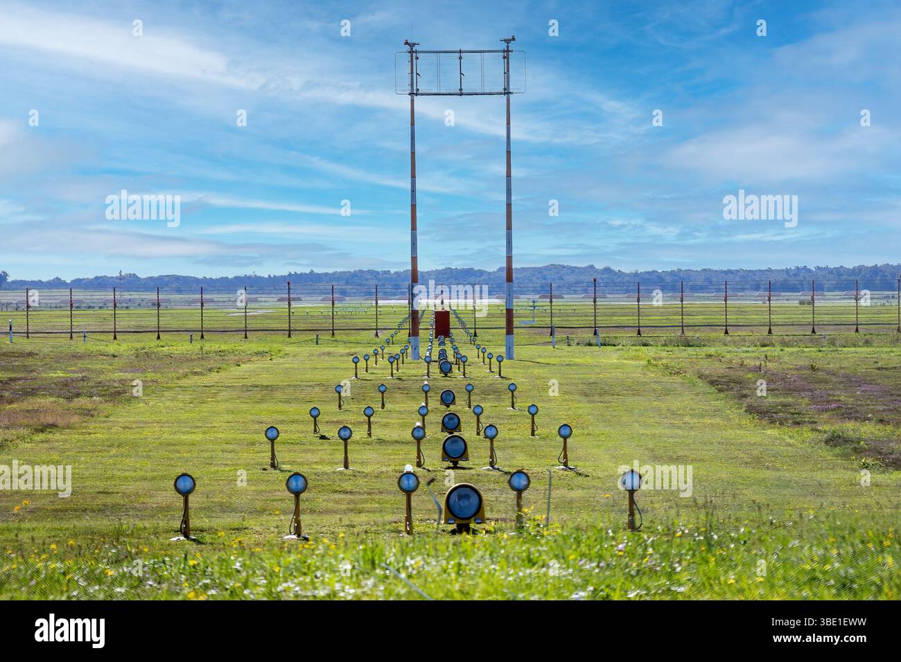 Rows of approach lights extending across grassy area towards runway ...