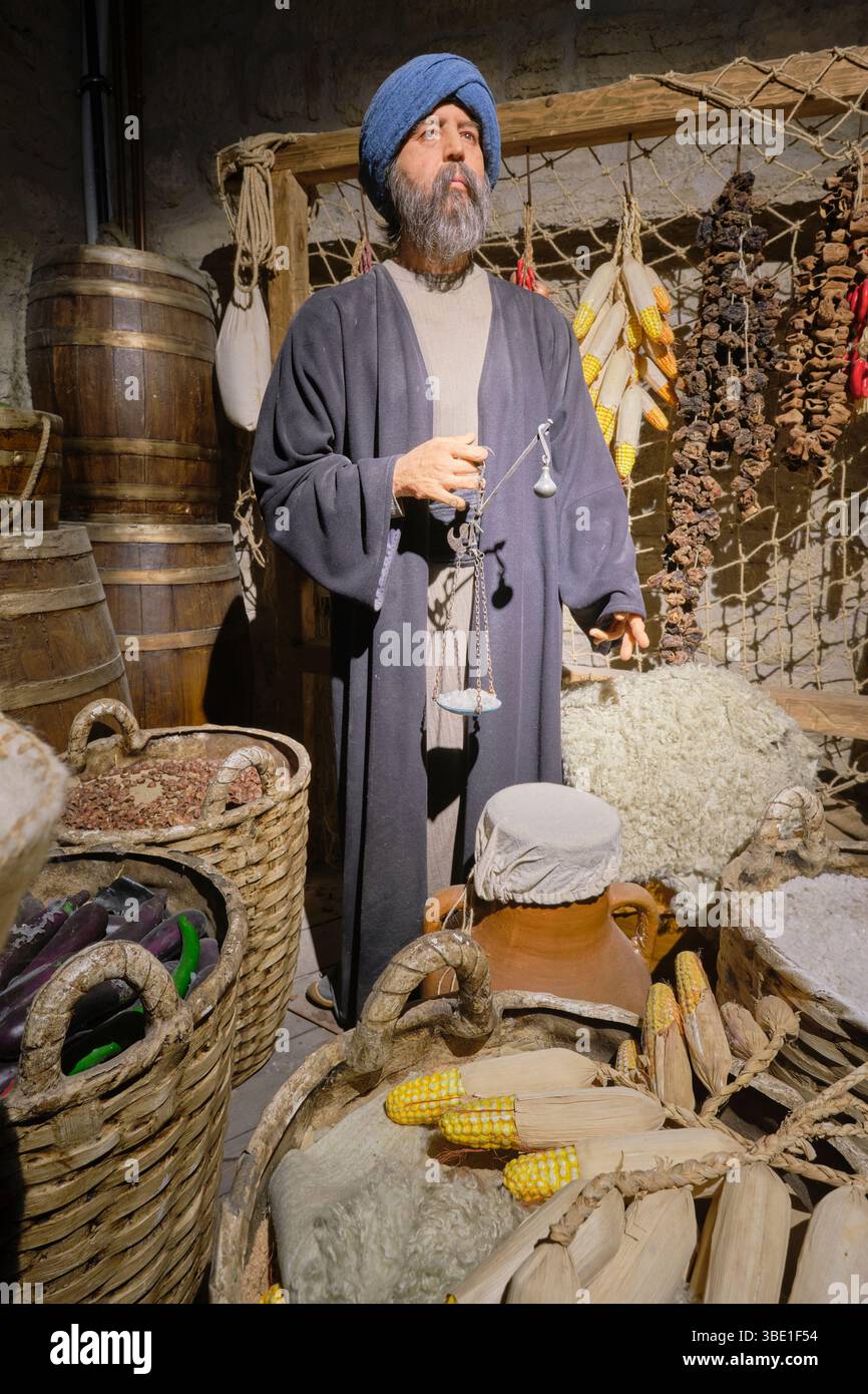 An old man merchant using a hand scale for a buyer at his stall at a ...