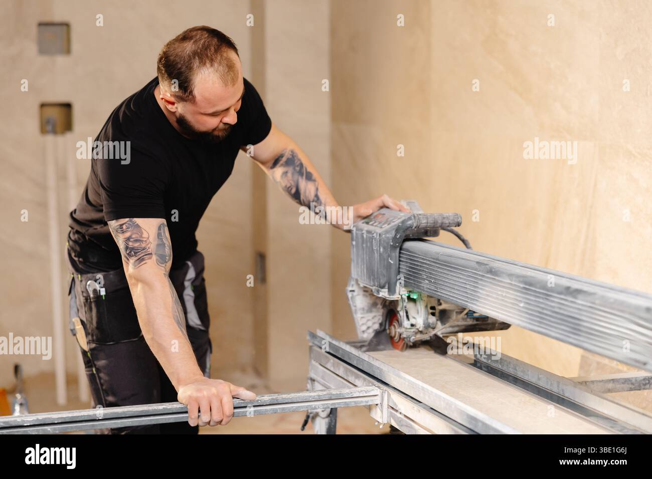 Construction worker carefully cutting ceramic tile using electric saw ...