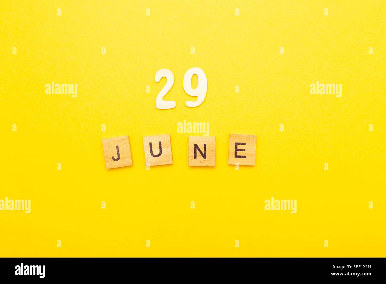 Top view of word 29 June calendar date made by wooden cubes on yellow ...