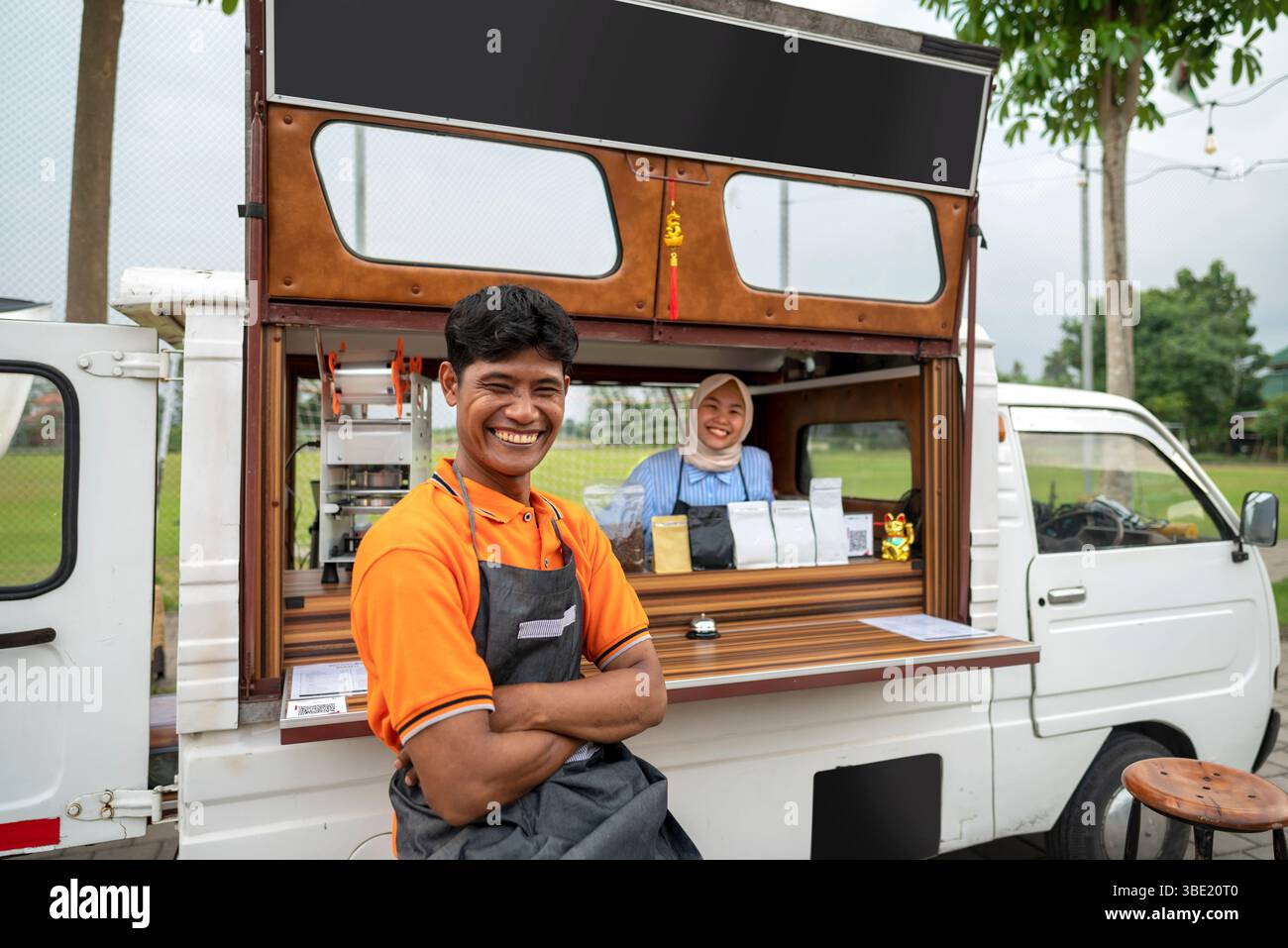Indonesian southeast asian male and a Chinese muslim female in hijab couple baristas with ...