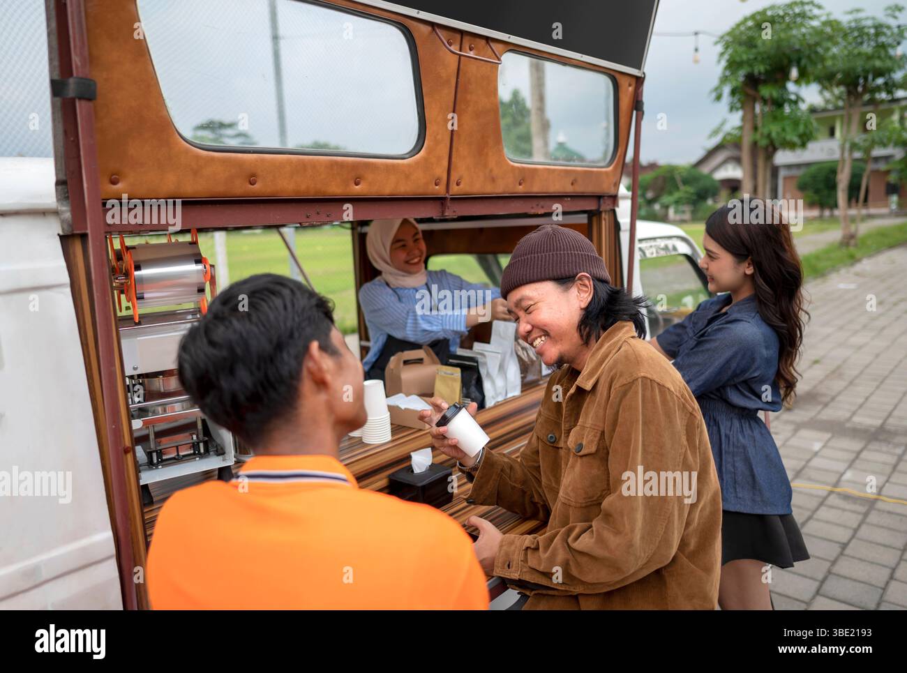 Chinese muslim female in a hijab waiter serving food to Indonesian ...