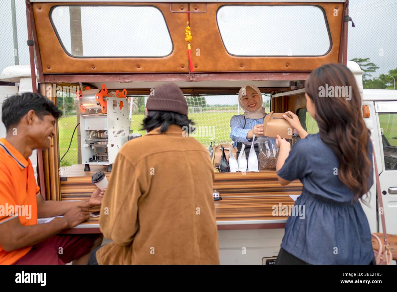 Chinese muslim female in a hijab waiter serving food to Indonesian ...