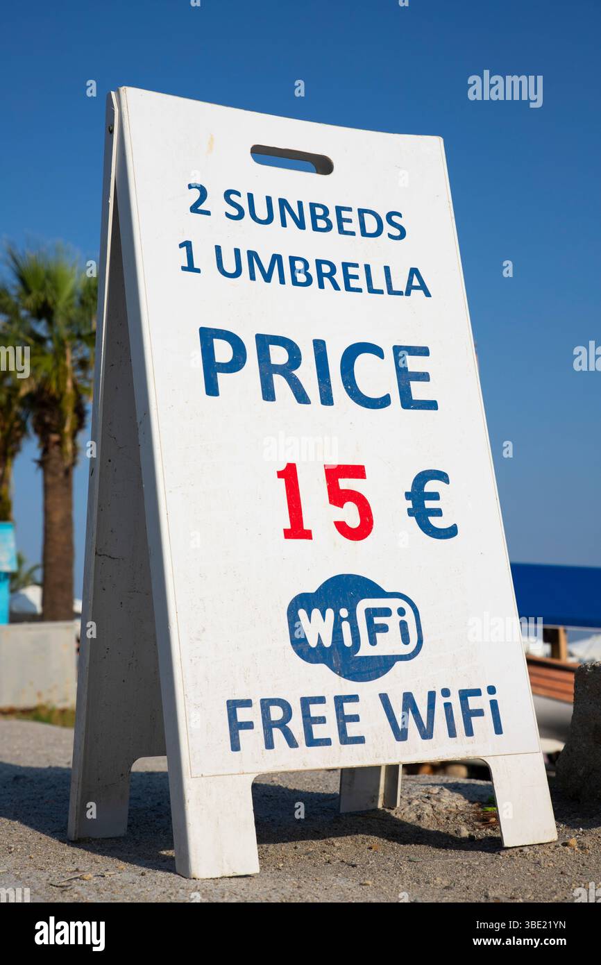 Chaniotis, Greece - September 05, 2024: Sunbeds and umbrella price sign ...
