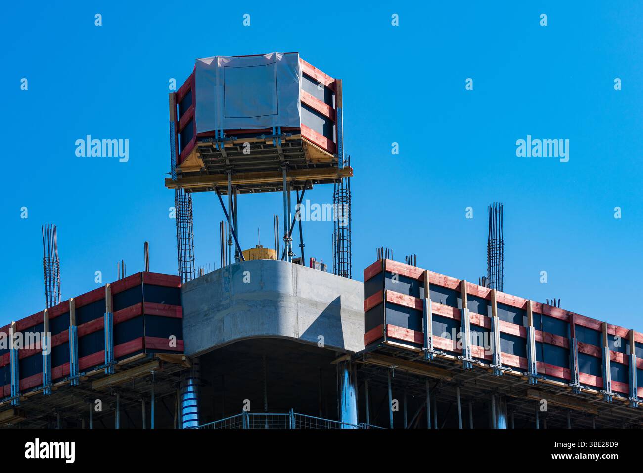 Workers are busy at the top of a high-rise building, overseeing ...